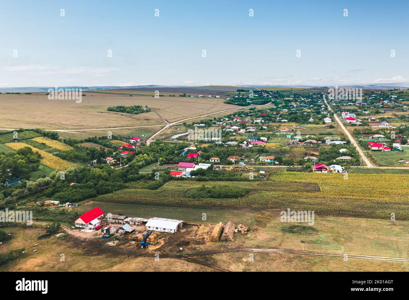 Aerial rural village landscape with yellow patched agriculture fields ...