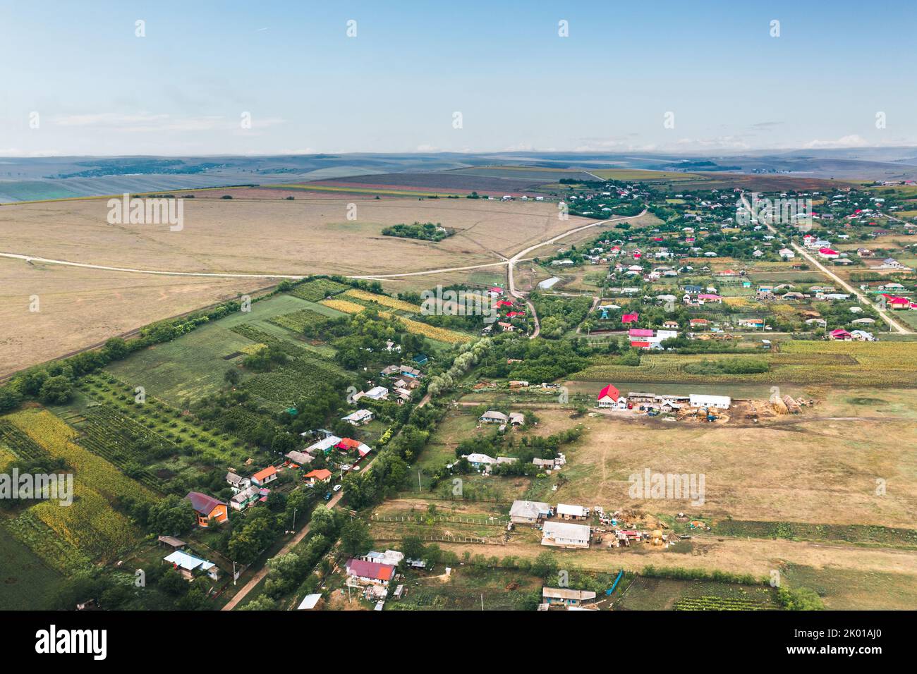 Aerial rural village landscape with yellow patched agriculture fields ...