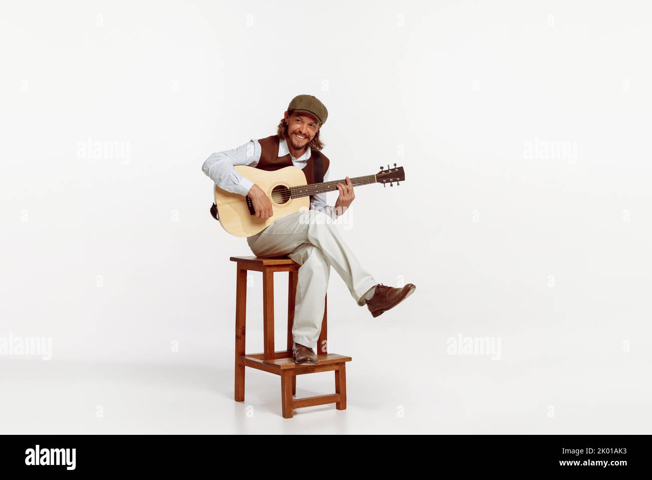 Portrait of stylish man playing guitar, performing isolated over white ...