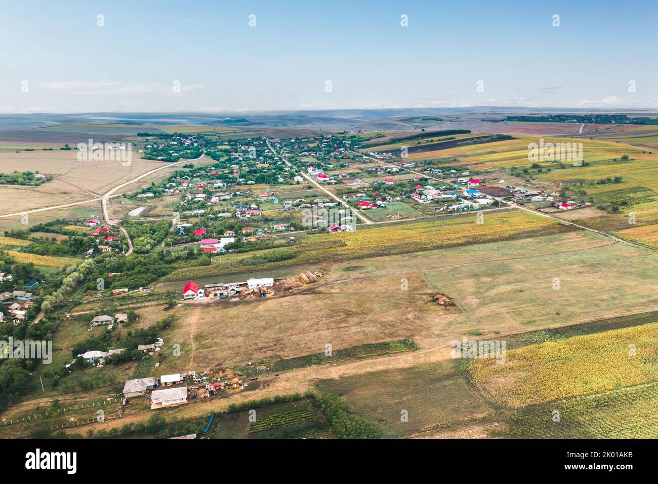 Aerial rural village landscape with yellow patched agriculture fields ...