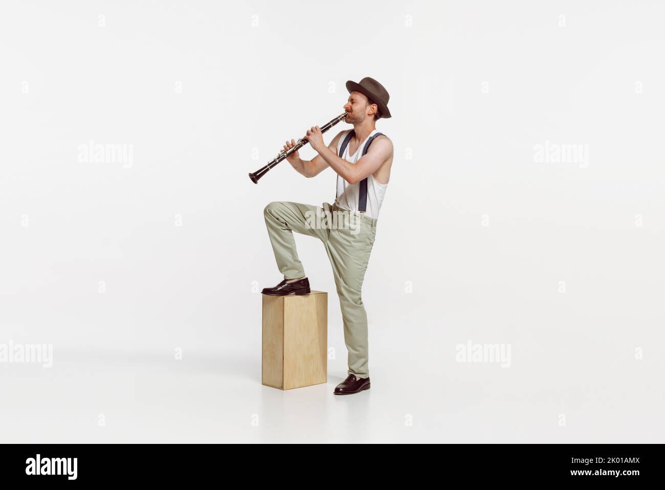 Portrait of young man playing clarinet isolated over white studio ...