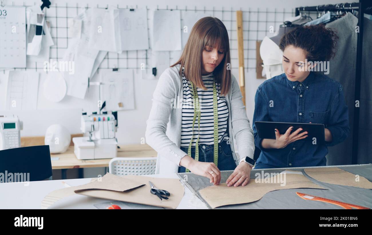 Female clothing designer is drawing outlines of new garment on fabric ...