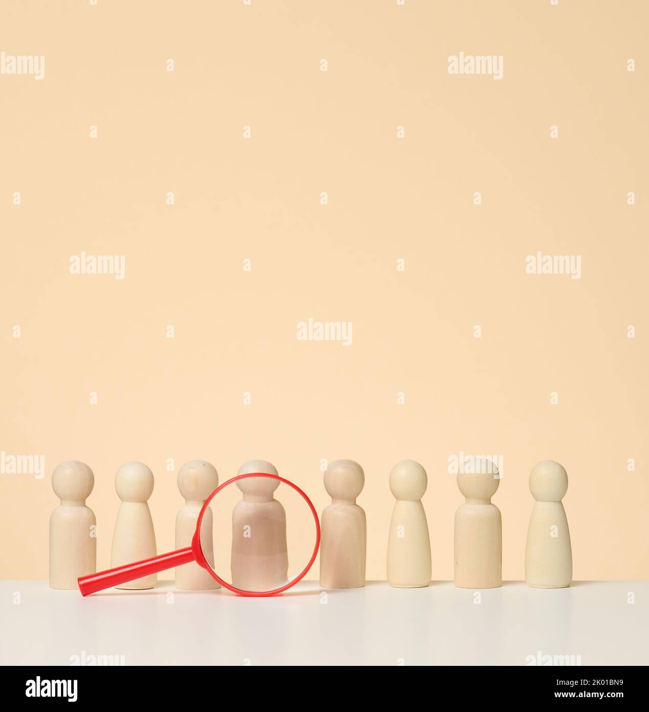 Wooden figures of men stand on a beige background and a blue plastic ...