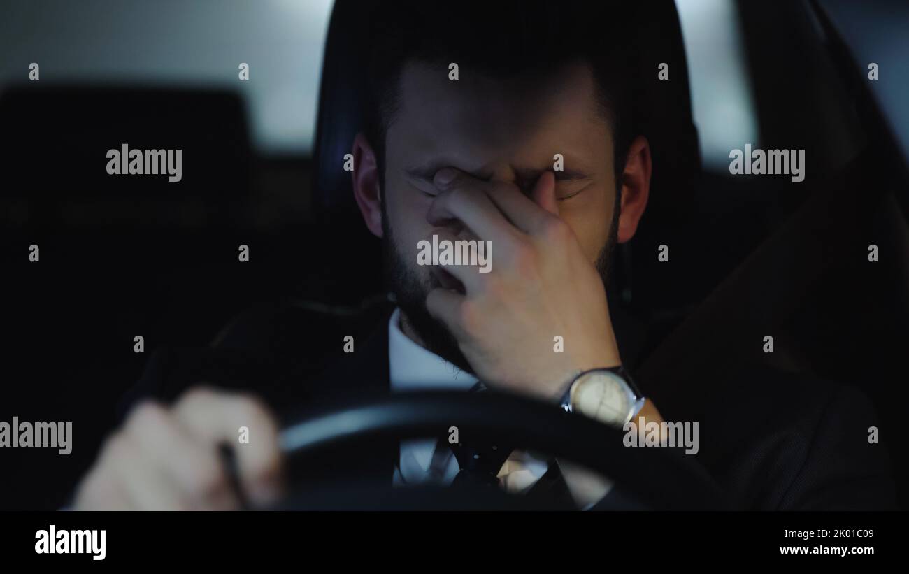 sleepy businessman touching eyes while driving car in evening,stock ...