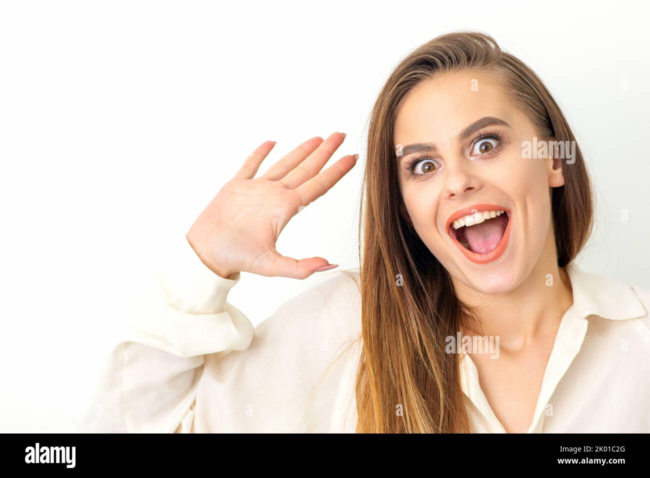 Portrait of young caucasian woman wearing white shirt raises hands and ...