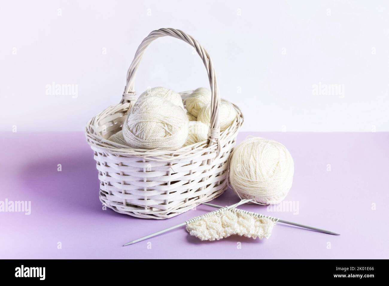 White balls of thread in a basket on a lilac background for knitting ...