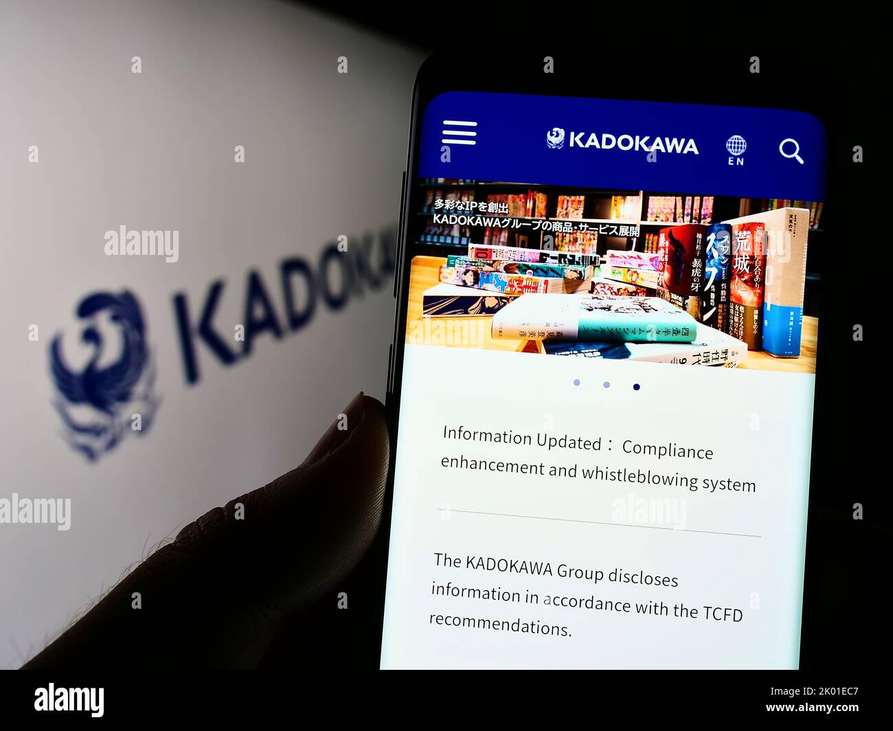 Person holding cellphone with website of Japanese media company ...