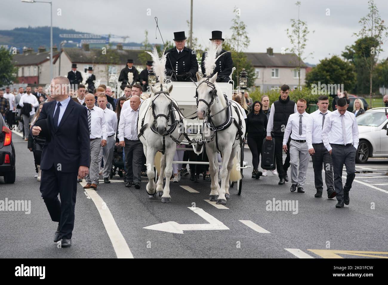 Mourners walk behind a horse drawn hearse carrying the coffins of Lisa ...