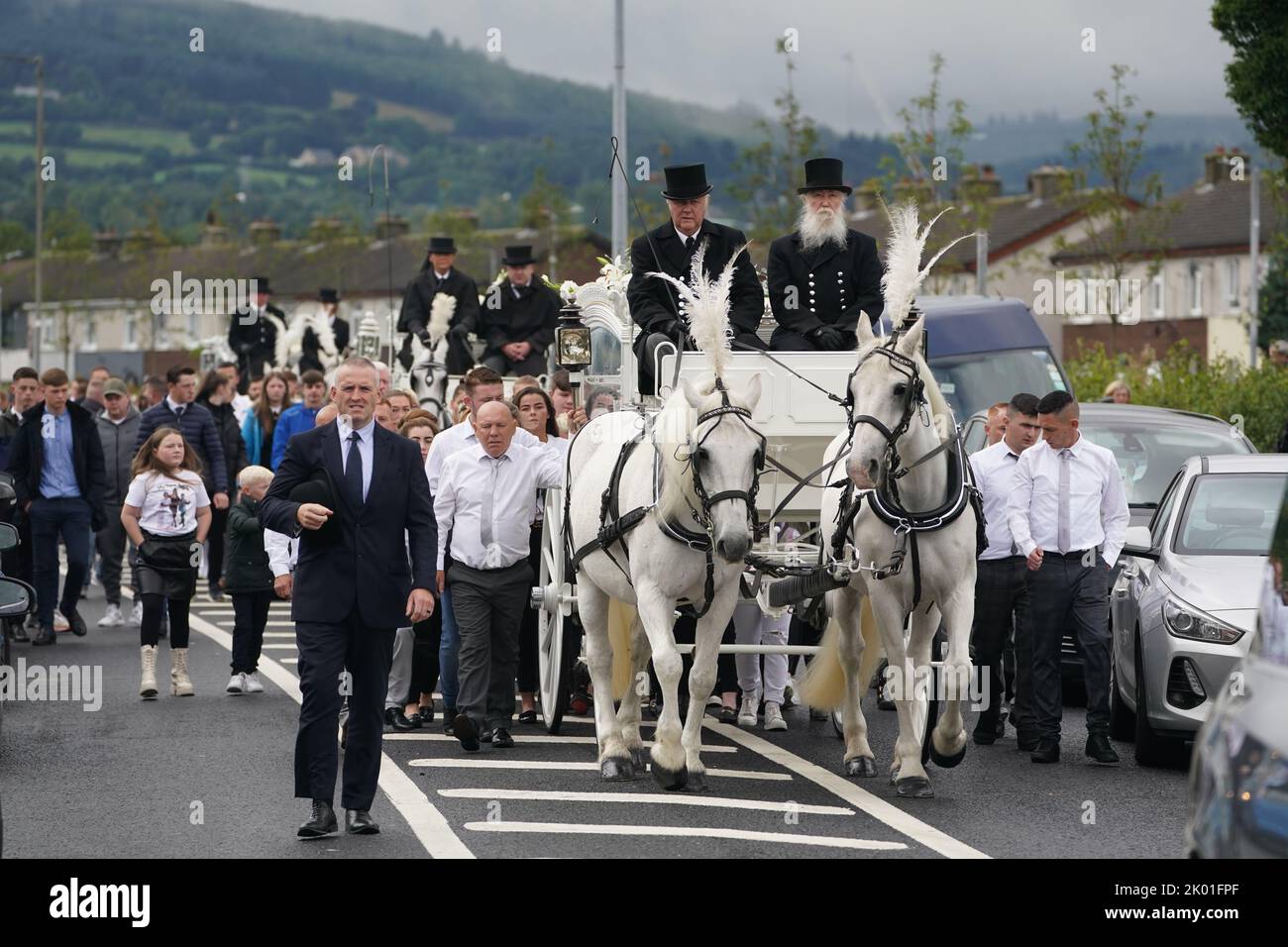 Mourners walk behind a horse drawn hearse carrying the coffins of Lisa ...