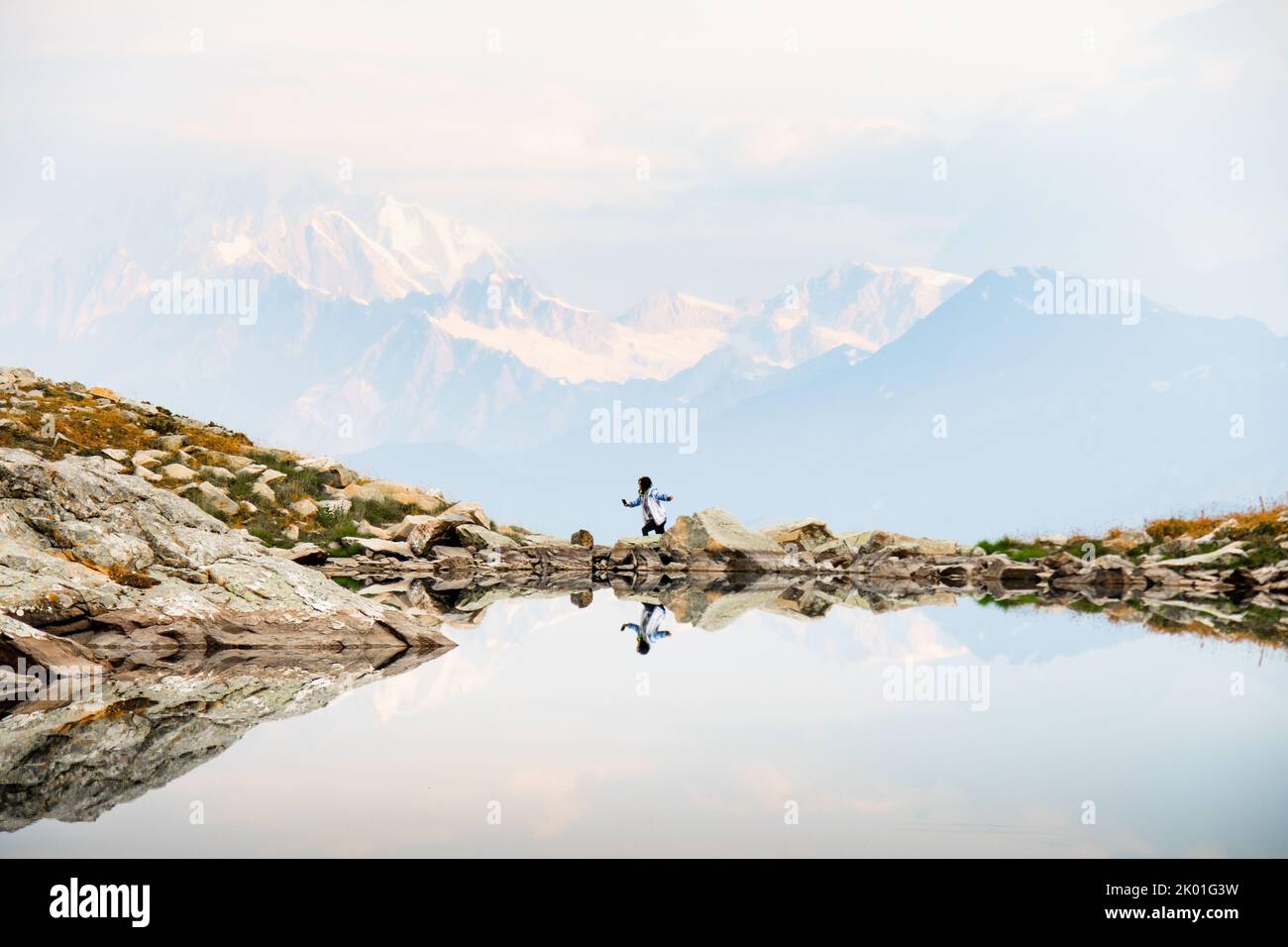 Woman figure solo jump from stone to rock on cliff viewpoint walk ...