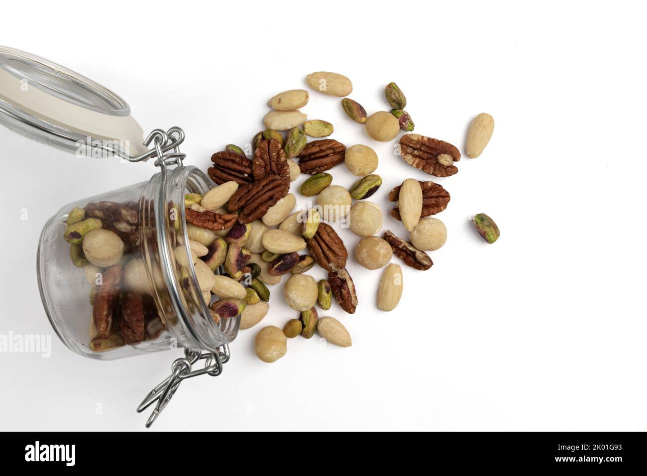 mixed nuts poured out of glass jar isolated on white background, top ...