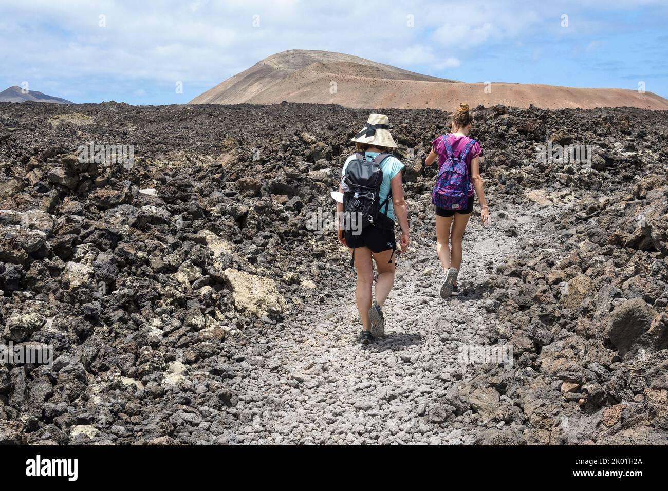 Two girls walking towards the Caldera Blanca volcano between lava and ...