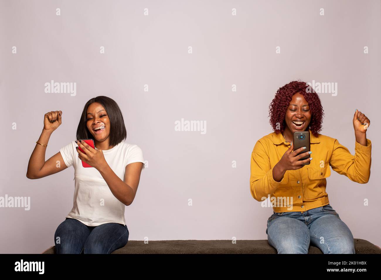 happy young black women checking their phones rejoicing Stock Photo - Alamy