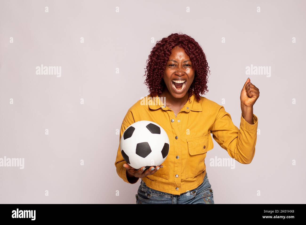 excited black lady holding a football celebrates Stock Photo - Alamy