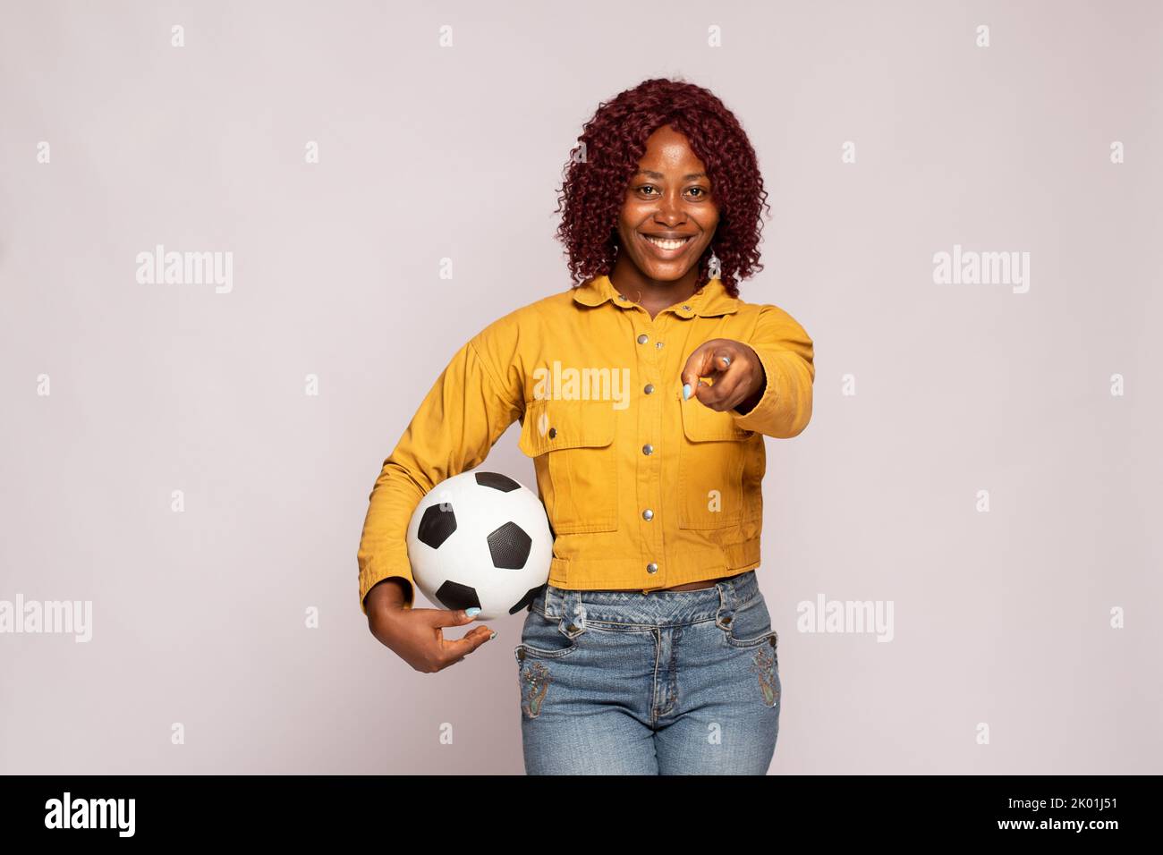 excited young black lady holding a football points forward Stock Photo ...