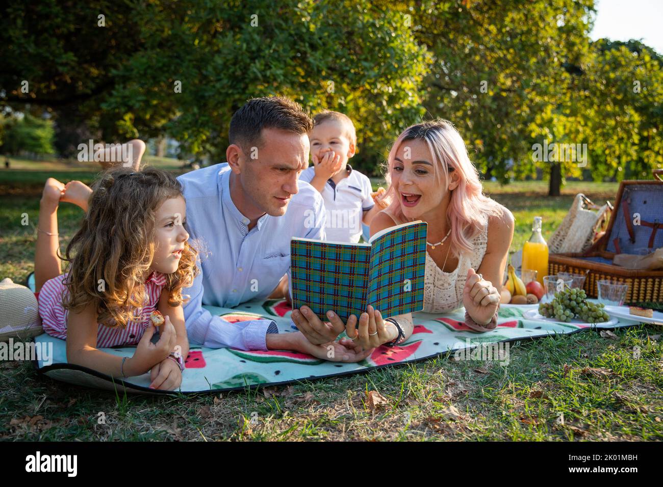 A happy family on a picnic, mother and father read fairy tales to ...
