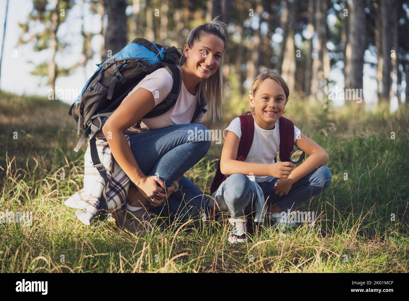 Mother and daughter explore with magnifying glass nature while hiking ...