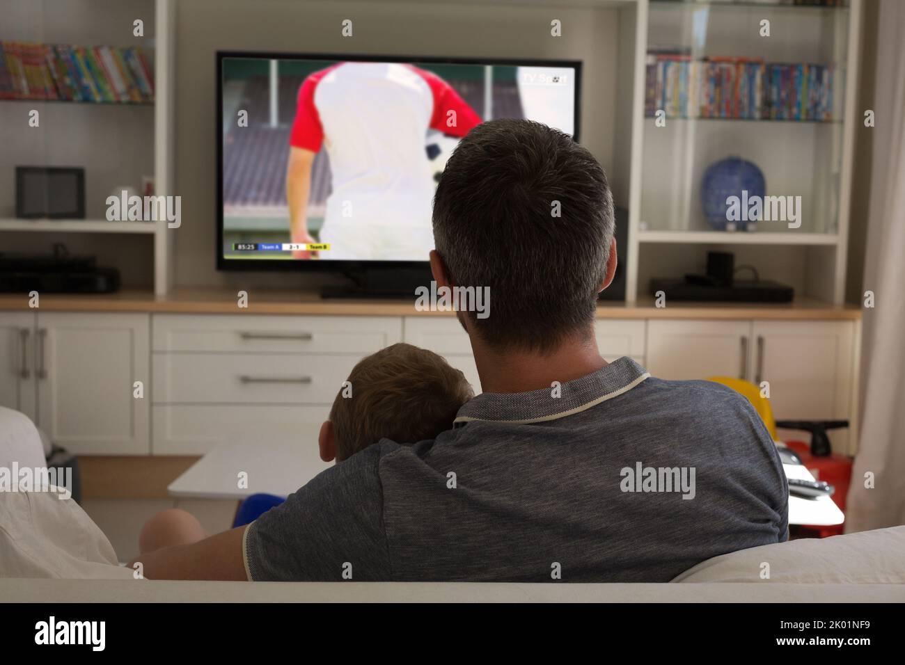 Caucasian father and son watching football match together and sitting ...