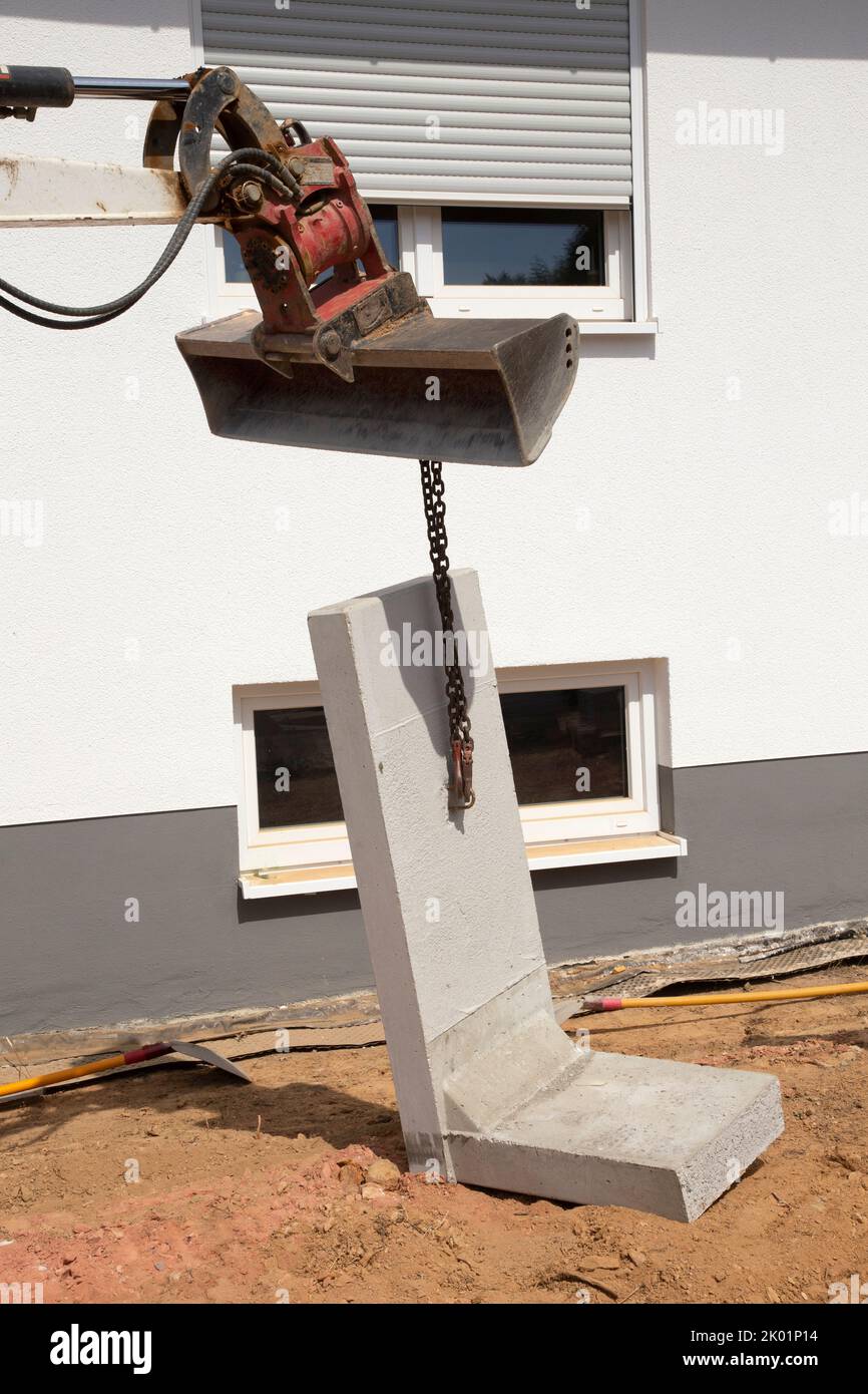L stones or angle concrete stones at the construction site hanging on a crane shovel to be ...