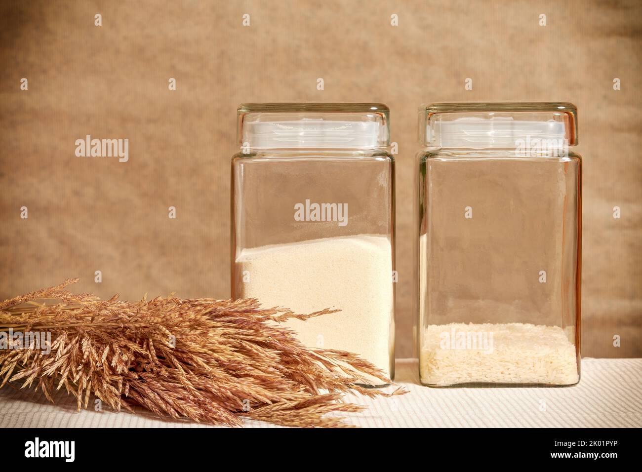 Semolina and cereals on the table in large jars. Ear of wheat for ...