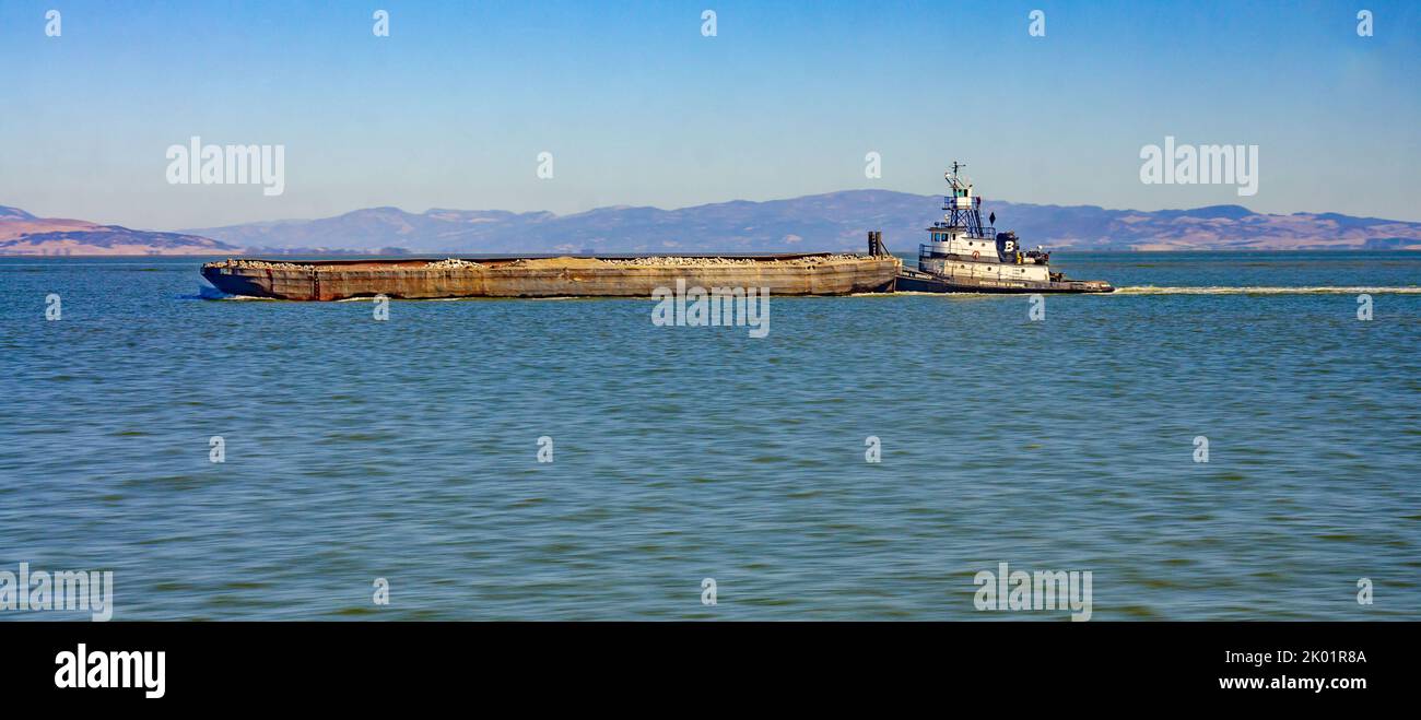 A tug boat pushes a barge full of aggregate across San Francisco Bay in ...
