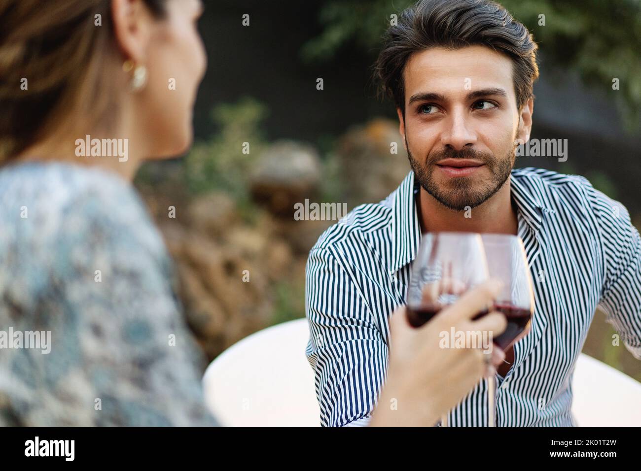 Couple of young people flirting on a date at outdoors restaurant looking each other and ...