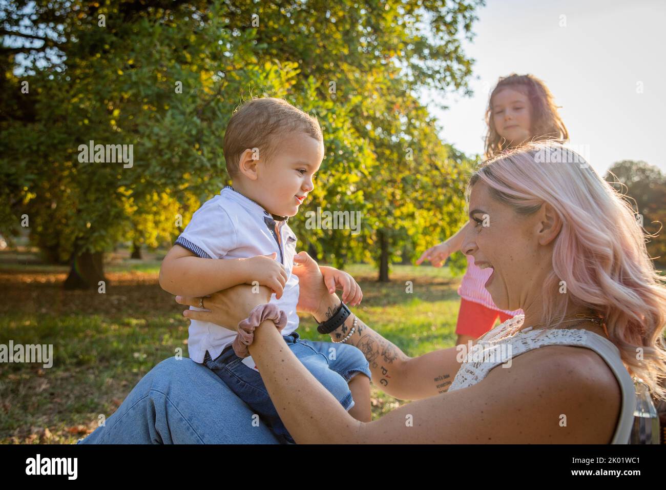 Mother plays with her son and makes him sit on her lap, the daughter in ...