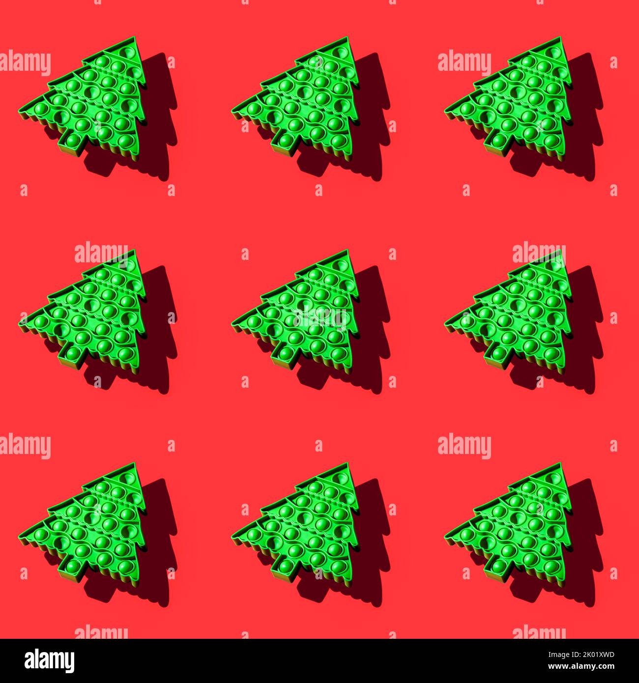 Green anti stress pop it toy for child in form of Christmas tree on red ...