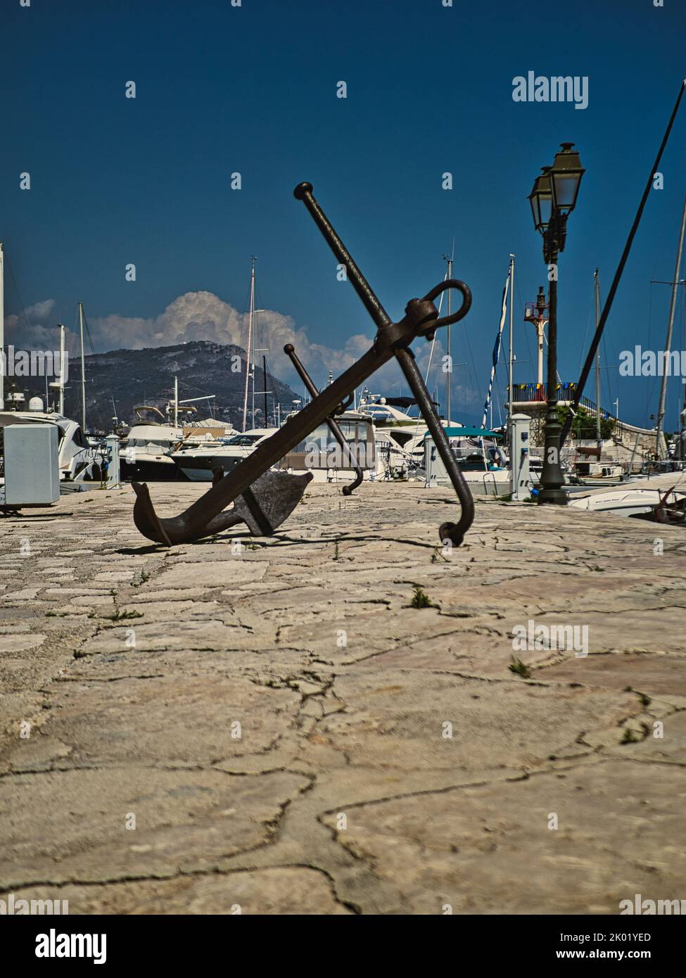 A vertical closeup shot of a black anchor on the rocky port ground ...