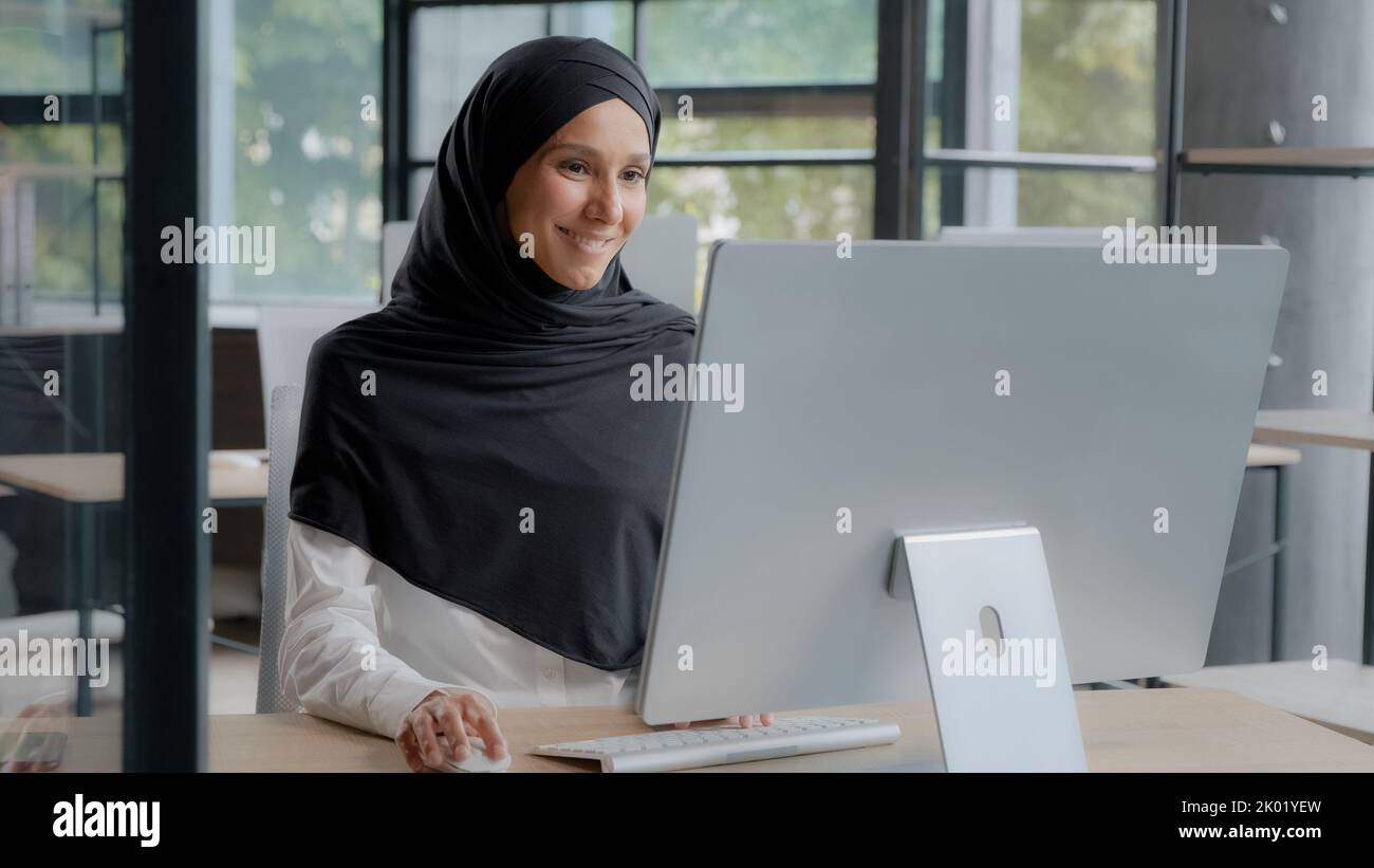 Happy successful arab businesswoman in hijab typing on keyboard working ...
