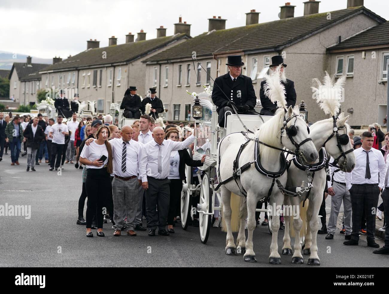 Mourners walk behind three horse drawn hearses carrying the coffins of ...