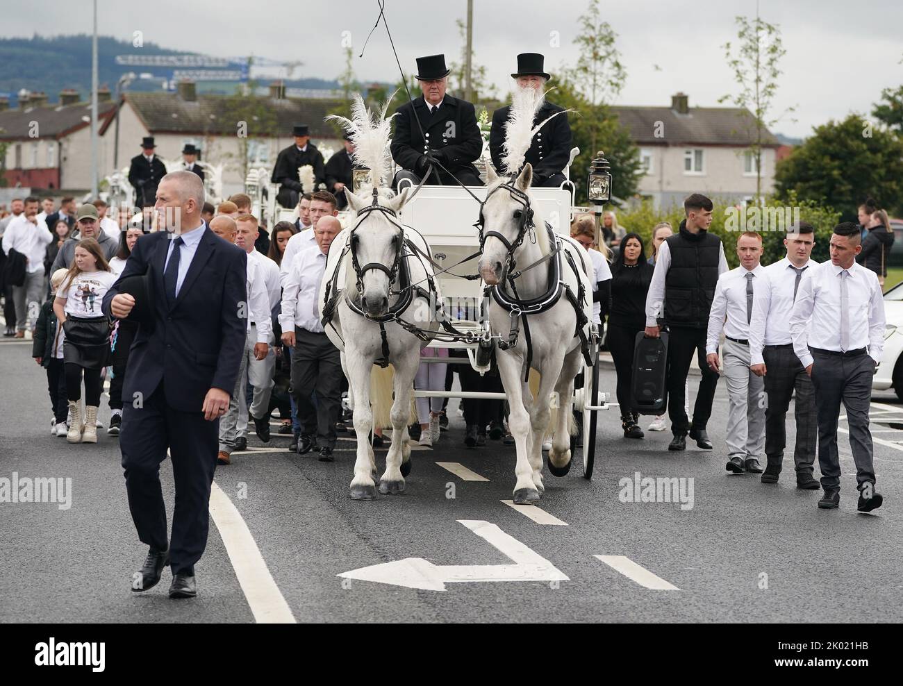 Mourners walk behind a horse drawn hearse carrying the coffins of Lisa ...