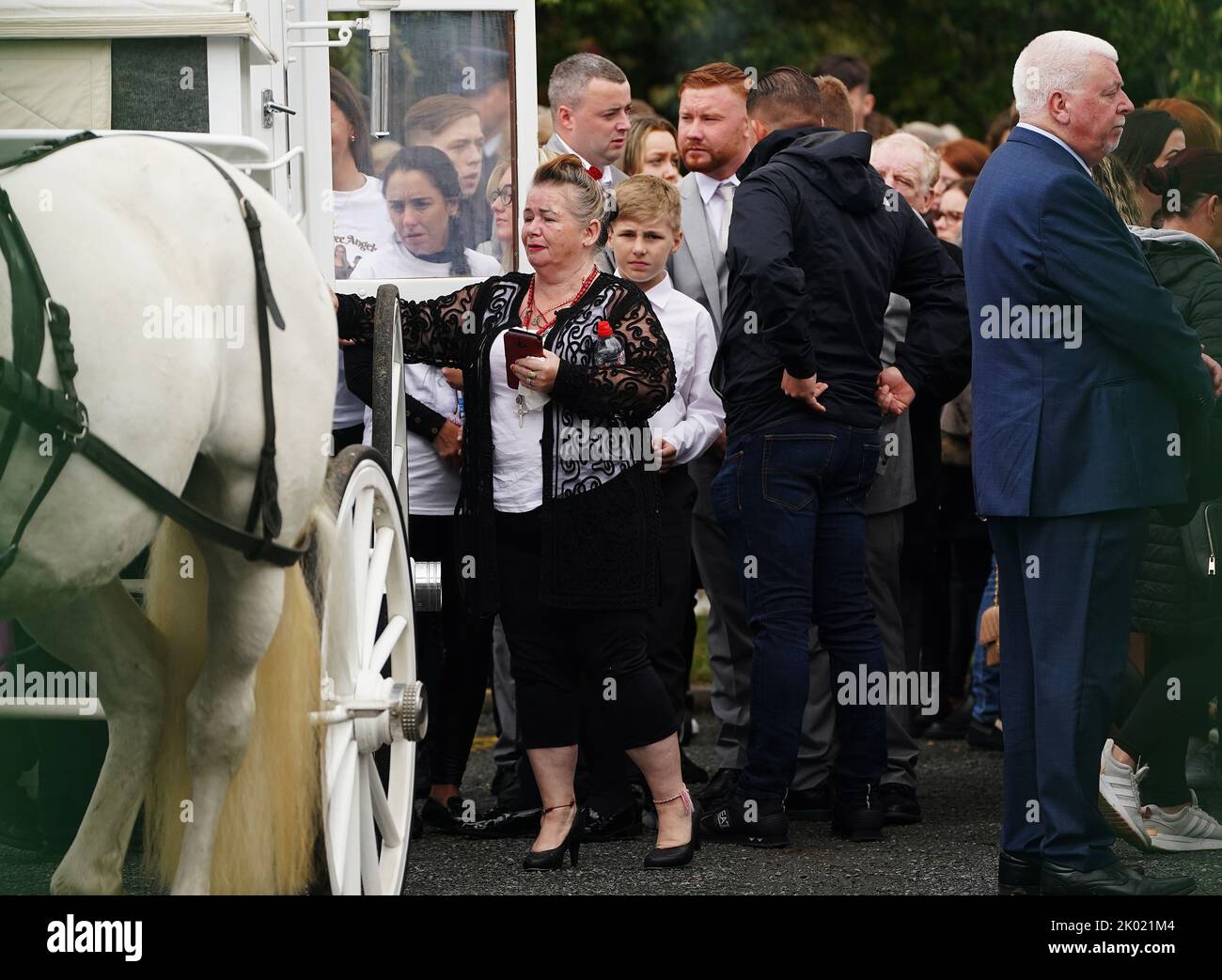Mourners gather around the horse drawn hearses following the funeral ...