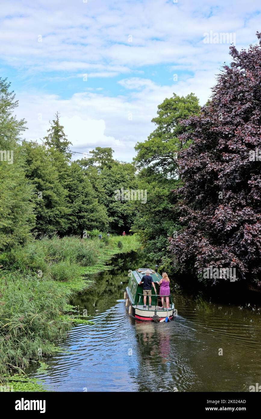 An elevated view of a small narrow boat cruising along the River Wey ...