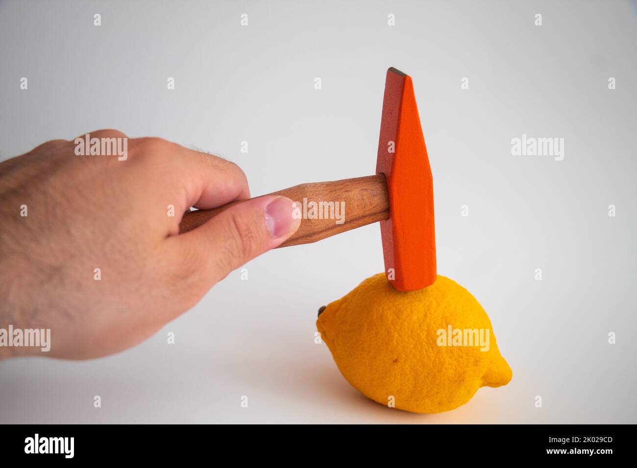 Hand held wooden handle hammer and orange head, on the lemon, isolated ...