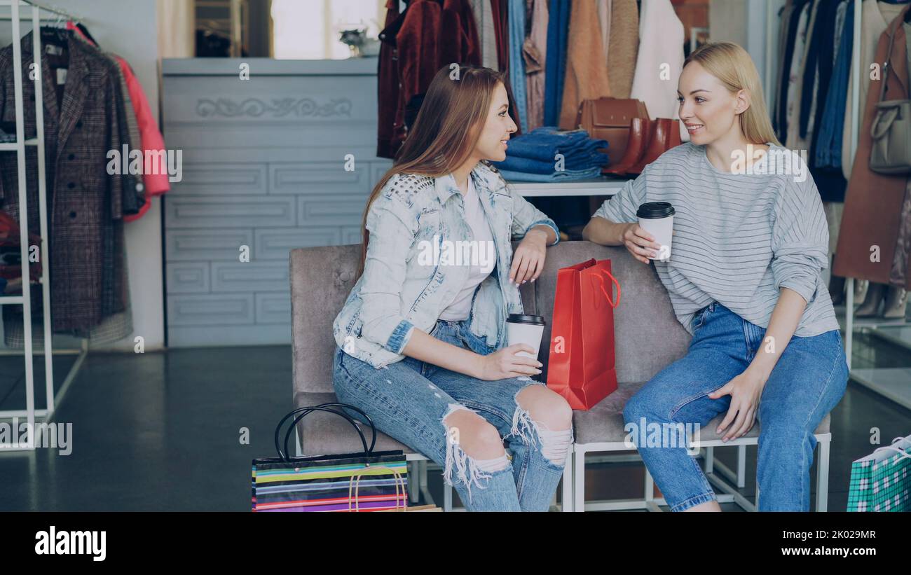 Two young attractive ladies sitting in clothes department in mall and ...