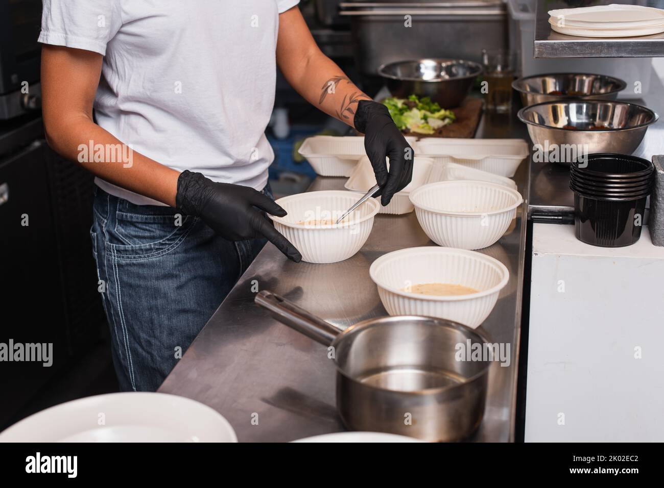 cropped view of tattooed african american woman holding plastic bowl ...