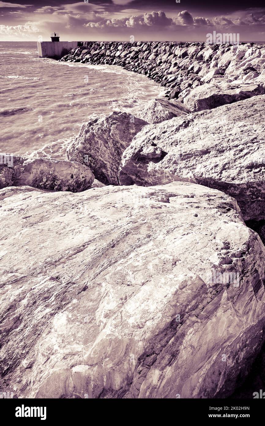 Dam with stone blocks for protection from sea storms with lighthouse in ...