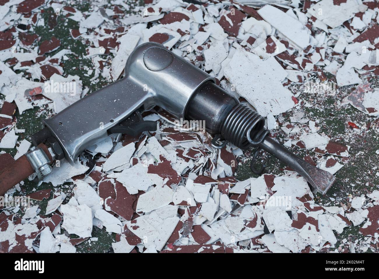 Pneumatic hammer on a background of pieces of old paint chipped off the ...