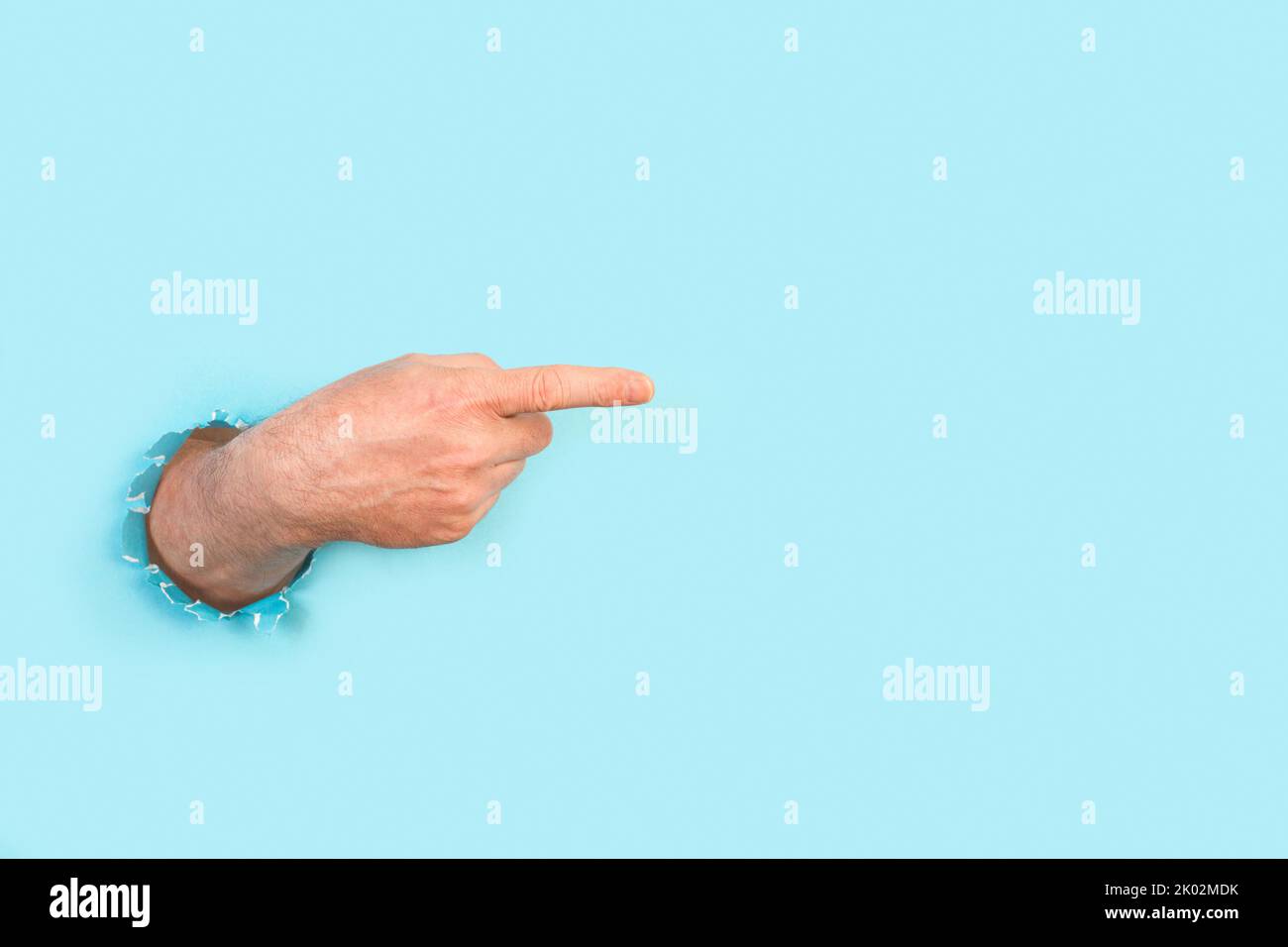 Man hand with pointing finger to the right through a hole in a light ...