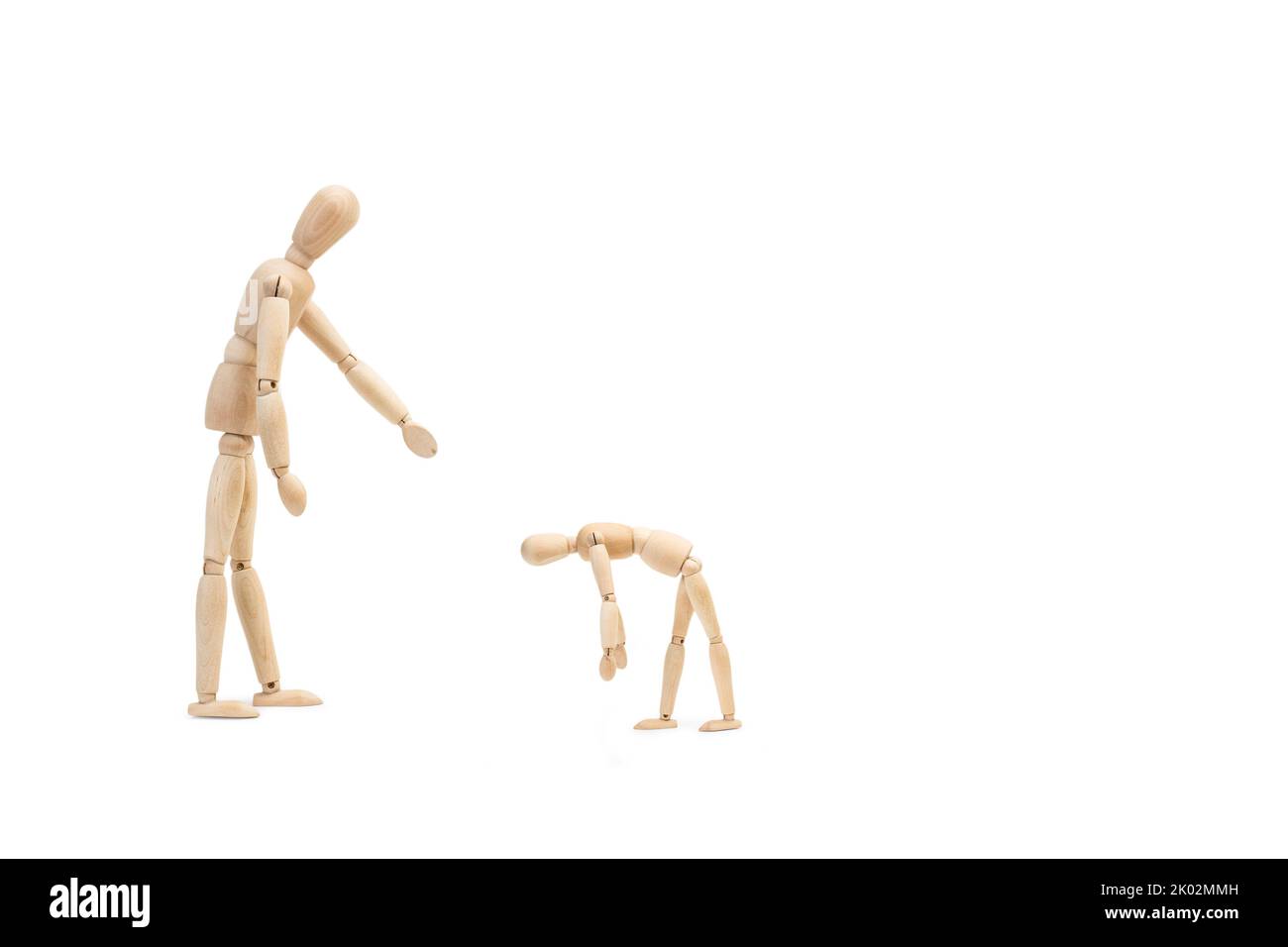 A wooden manequin toy with other small one in a submitted posture on a ...
