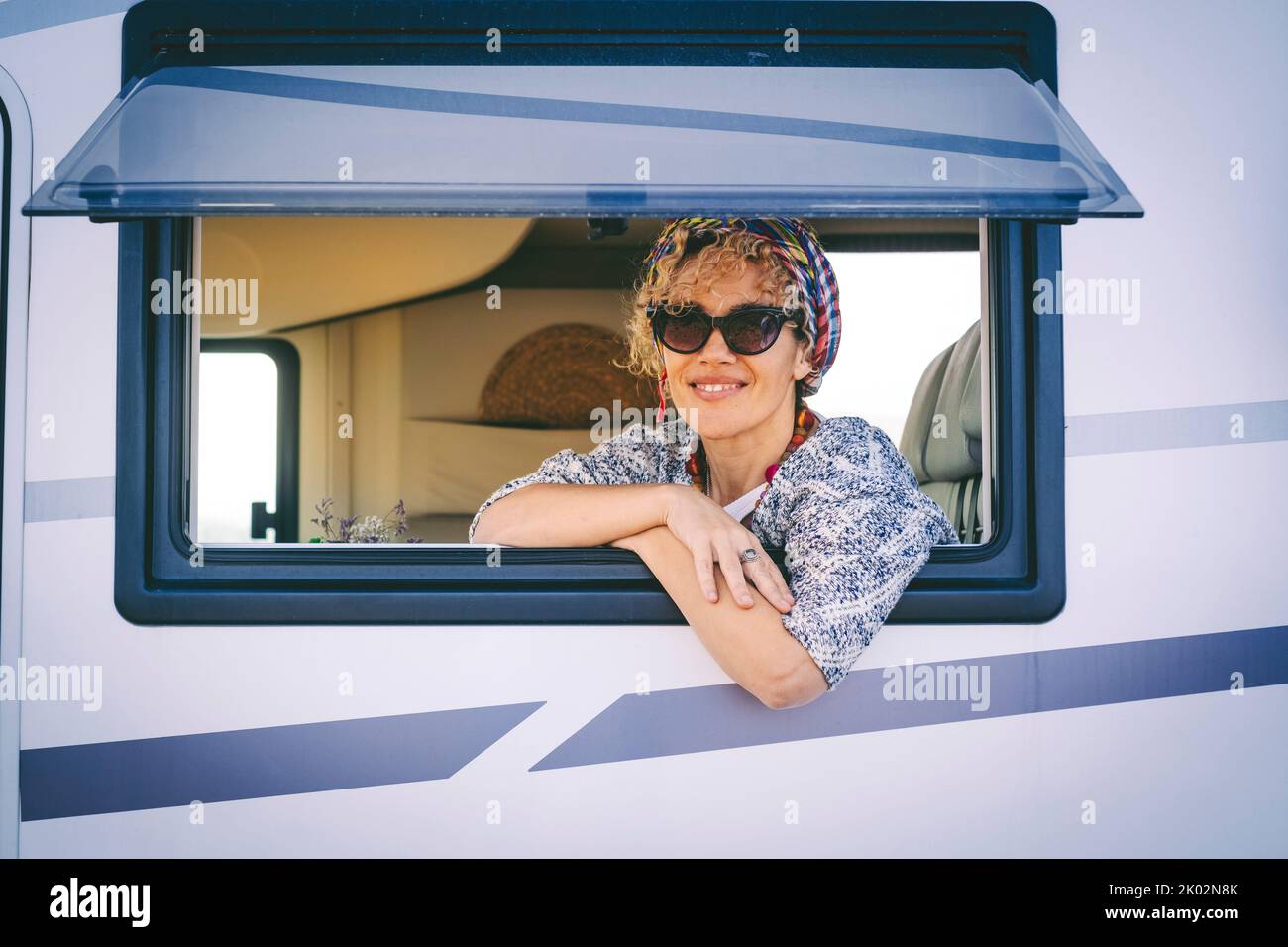 Portrait of young woman smiling at the camper van window. Happy tourist ...