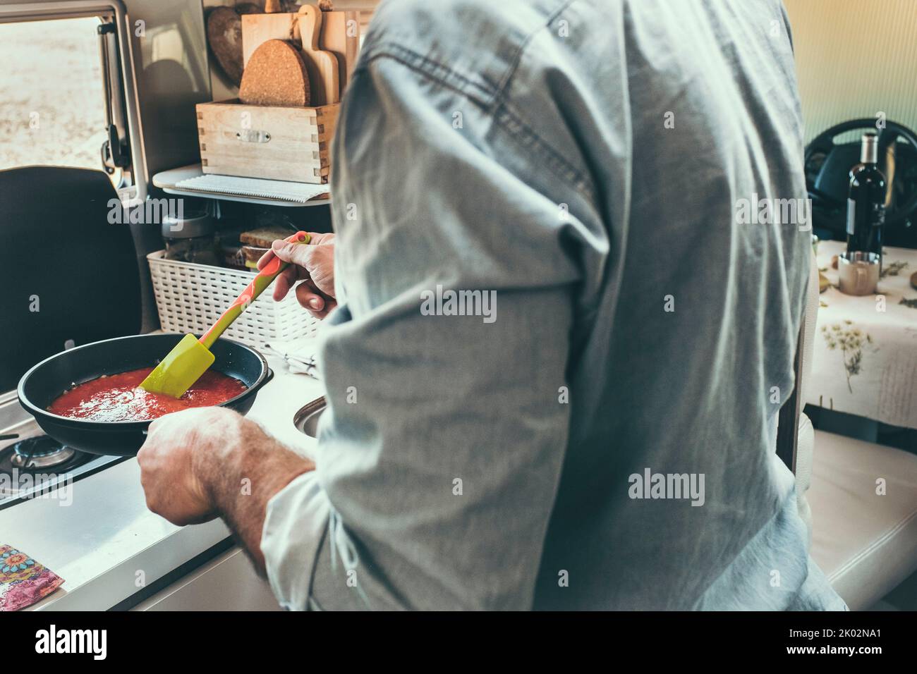 Back view of man cooking inside camper van in off grid van life ...