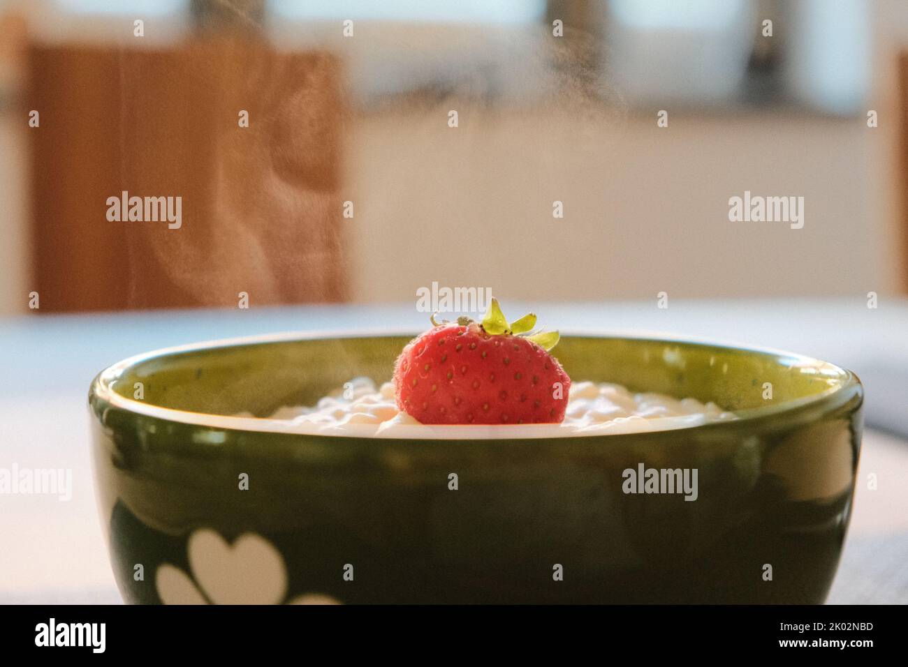 A selective focus shot of a bowl of hot cereal with a strawberry in the ...