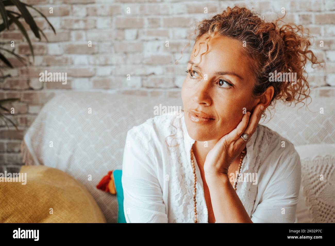 Portrait of serene woman looking outside the window at home having ...