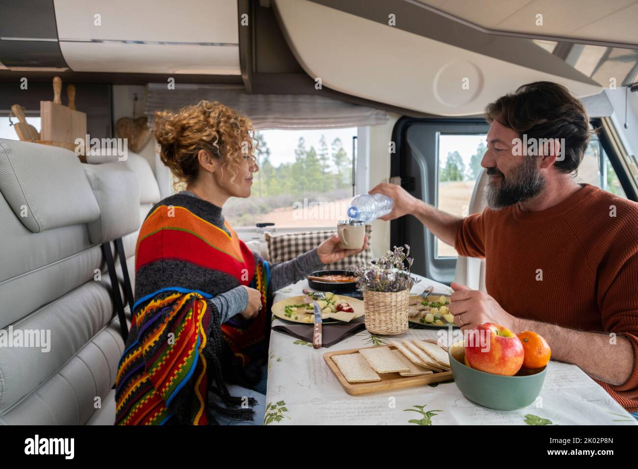 Adult couple enjoy time eating inside camper van in mountain holiday ...