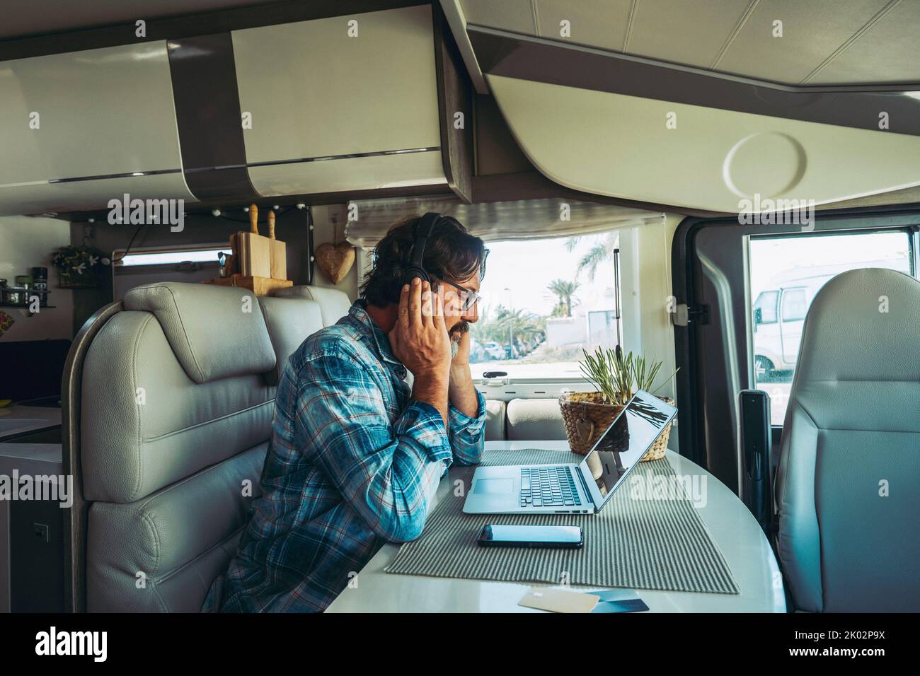 Adult man sitting at the desk using laptop computer and mobile phone ...