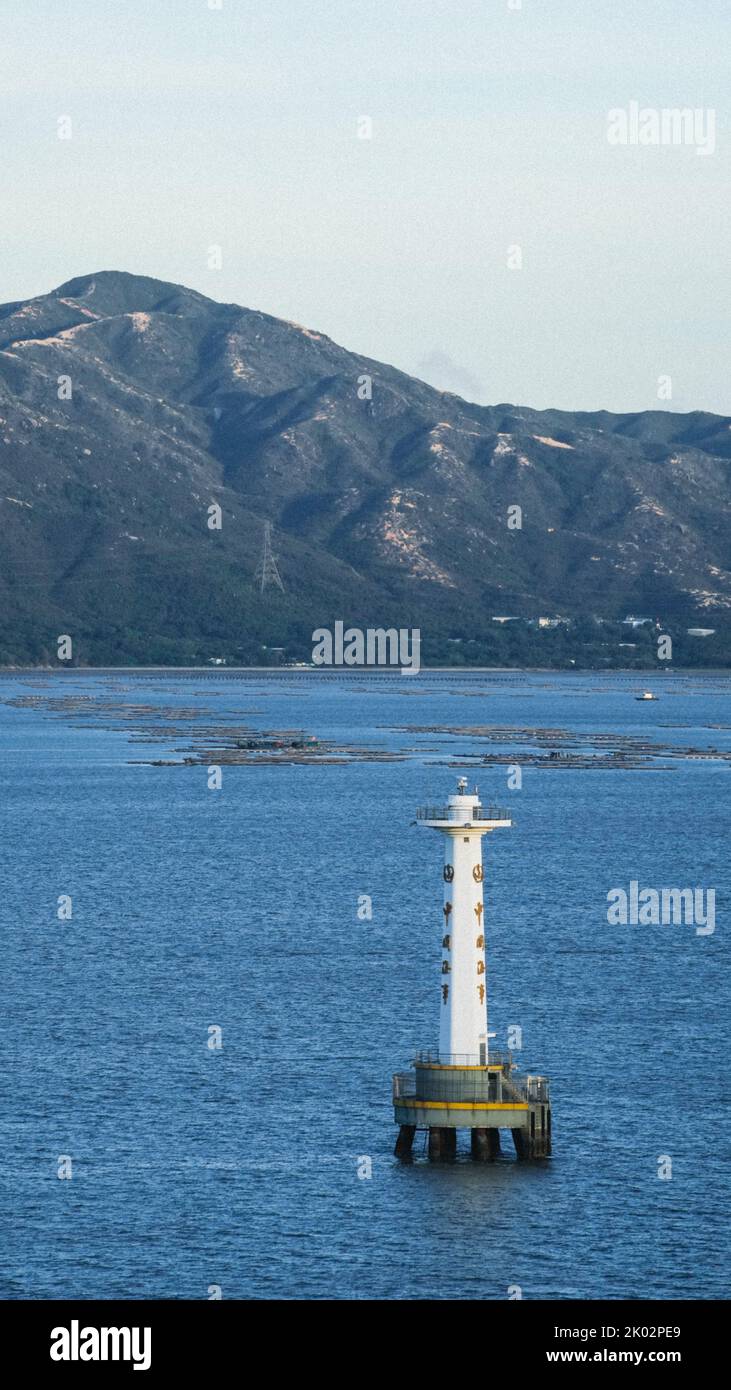 A vertical shot of a lighthouse in the beautiful blue sea with ...