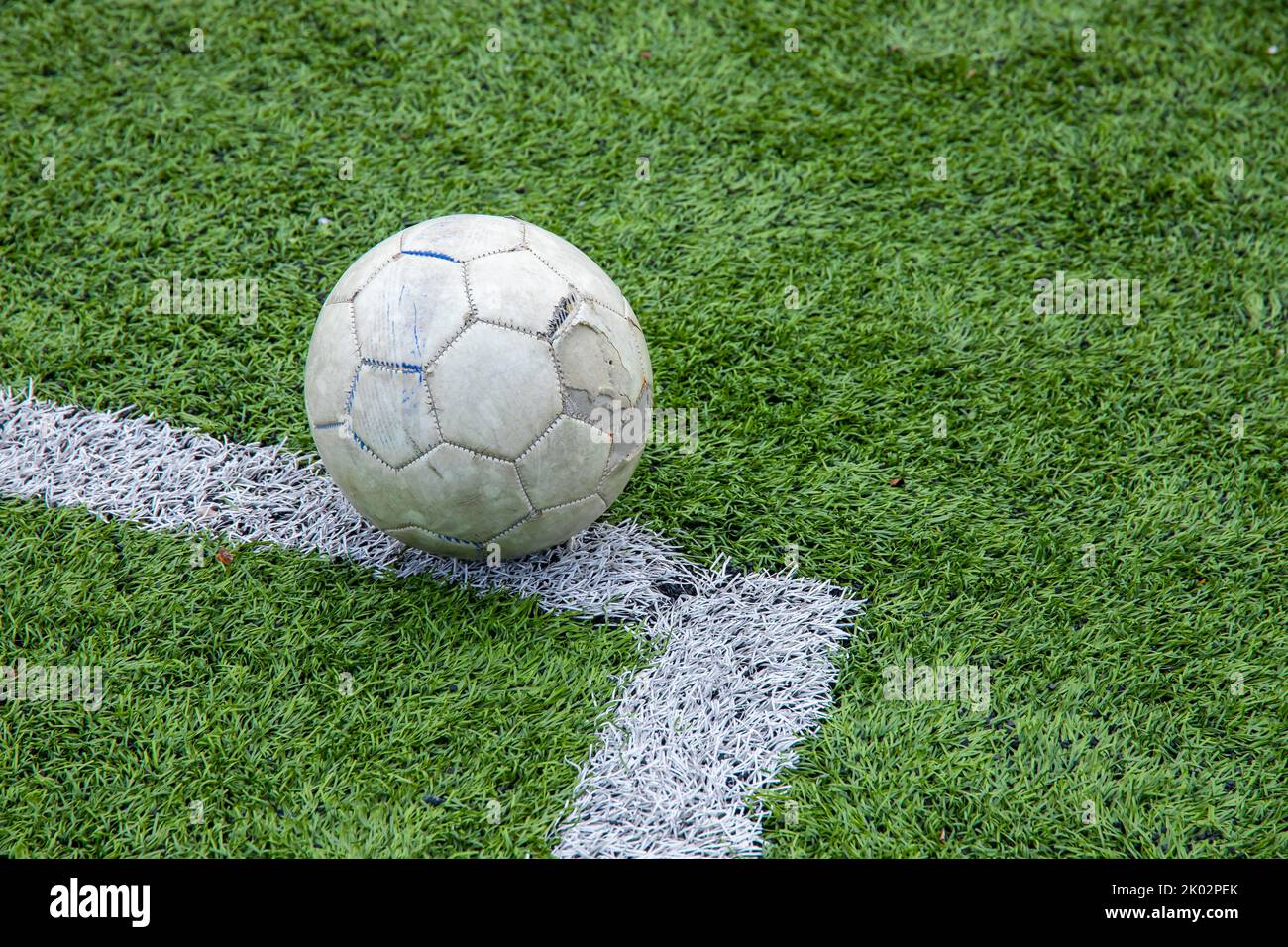A closeup of a white soccer ball standing on the white line in a soccer ...