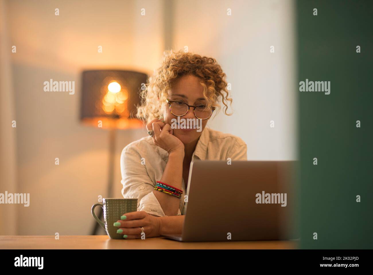 Adult woman working at laptop computer smiling and watching display ...